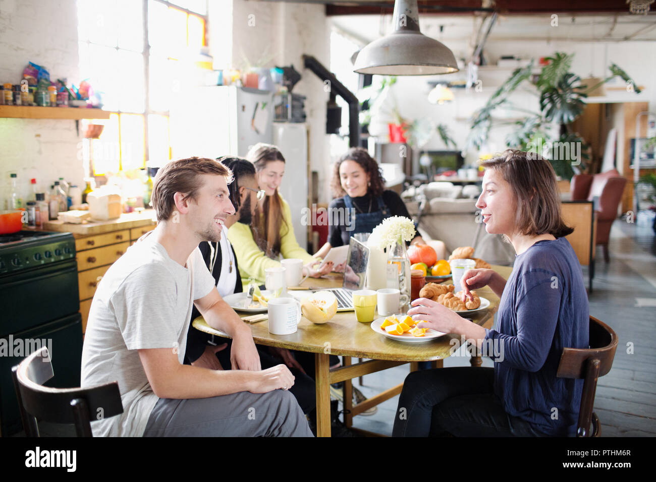 Young roommate friends enjoying breakfast at kitchen table in apartment ...