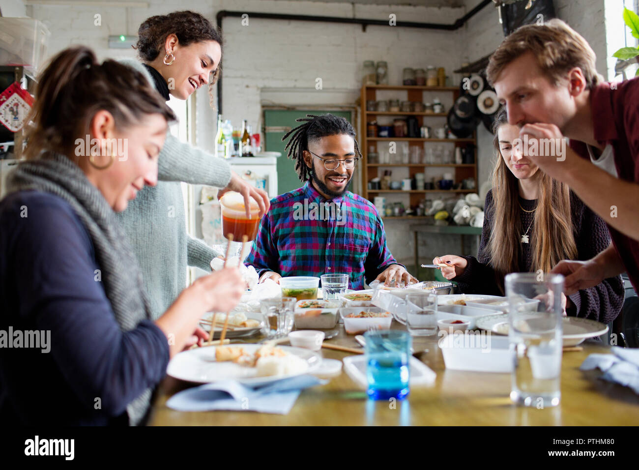 Young roommate friends enjoying takeout food at kitchen table in ...