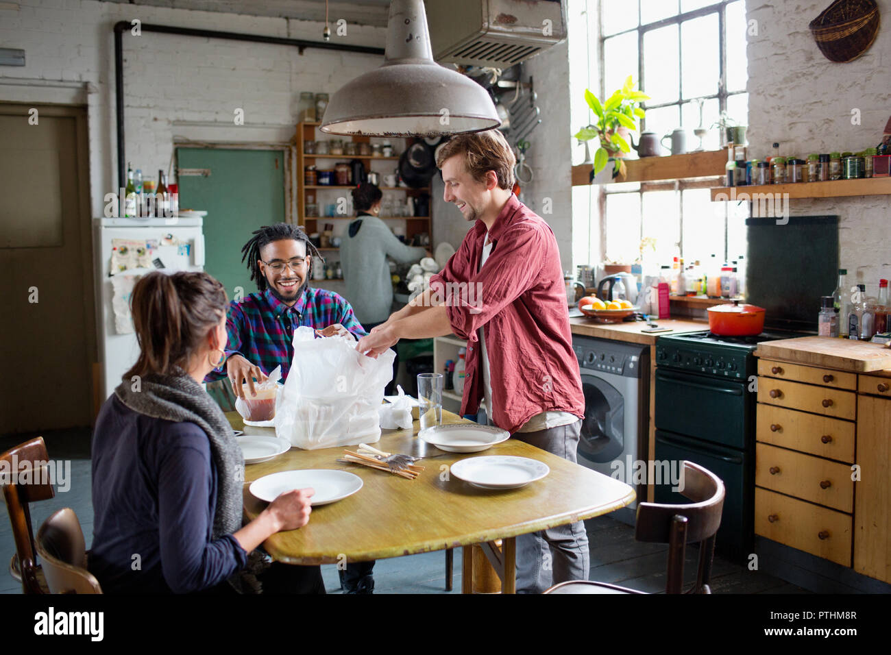 Young roommate friends preparing to eat takeout food at kitchen table ...