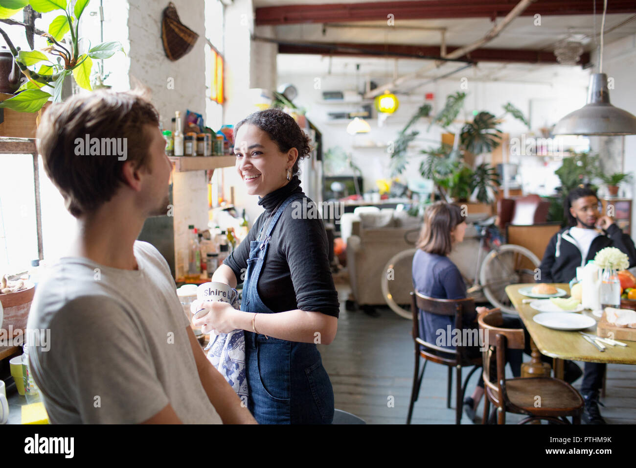 Young roommate friends doing dishes and talking in apartment kitchen ...