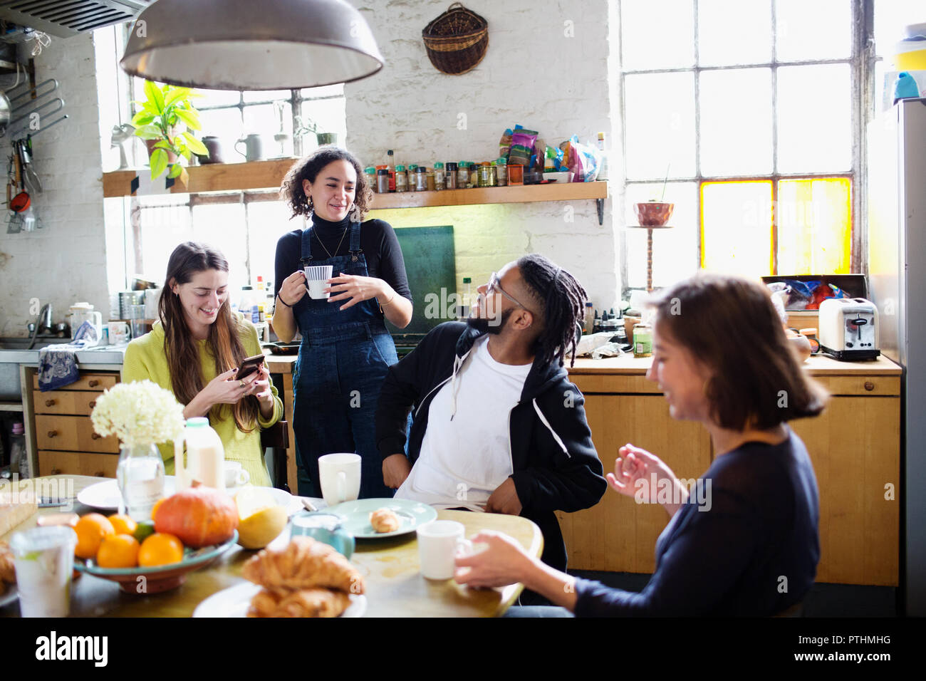 Young adult roommate friends talking at breakfast table in apartment ...