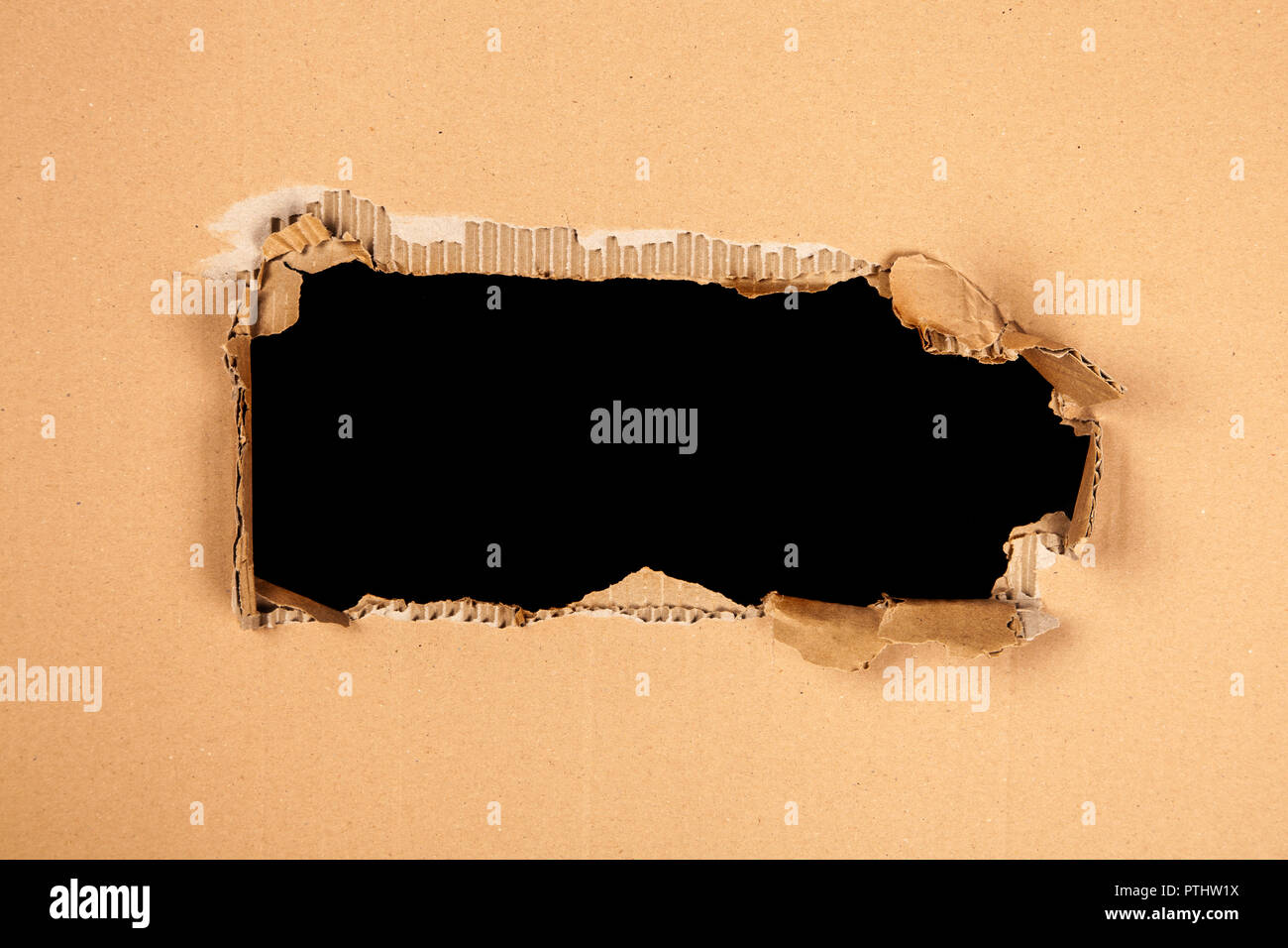 Cardboard with a hole - black background Stock Photo - Alamy