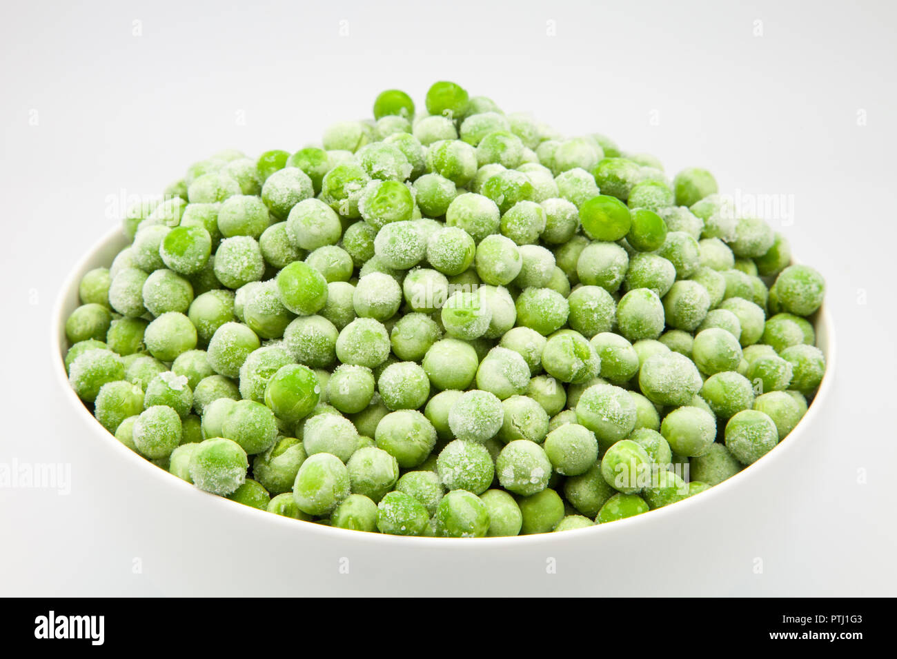 Frozen green peas in isolated white background Stock Photo - Alamy
