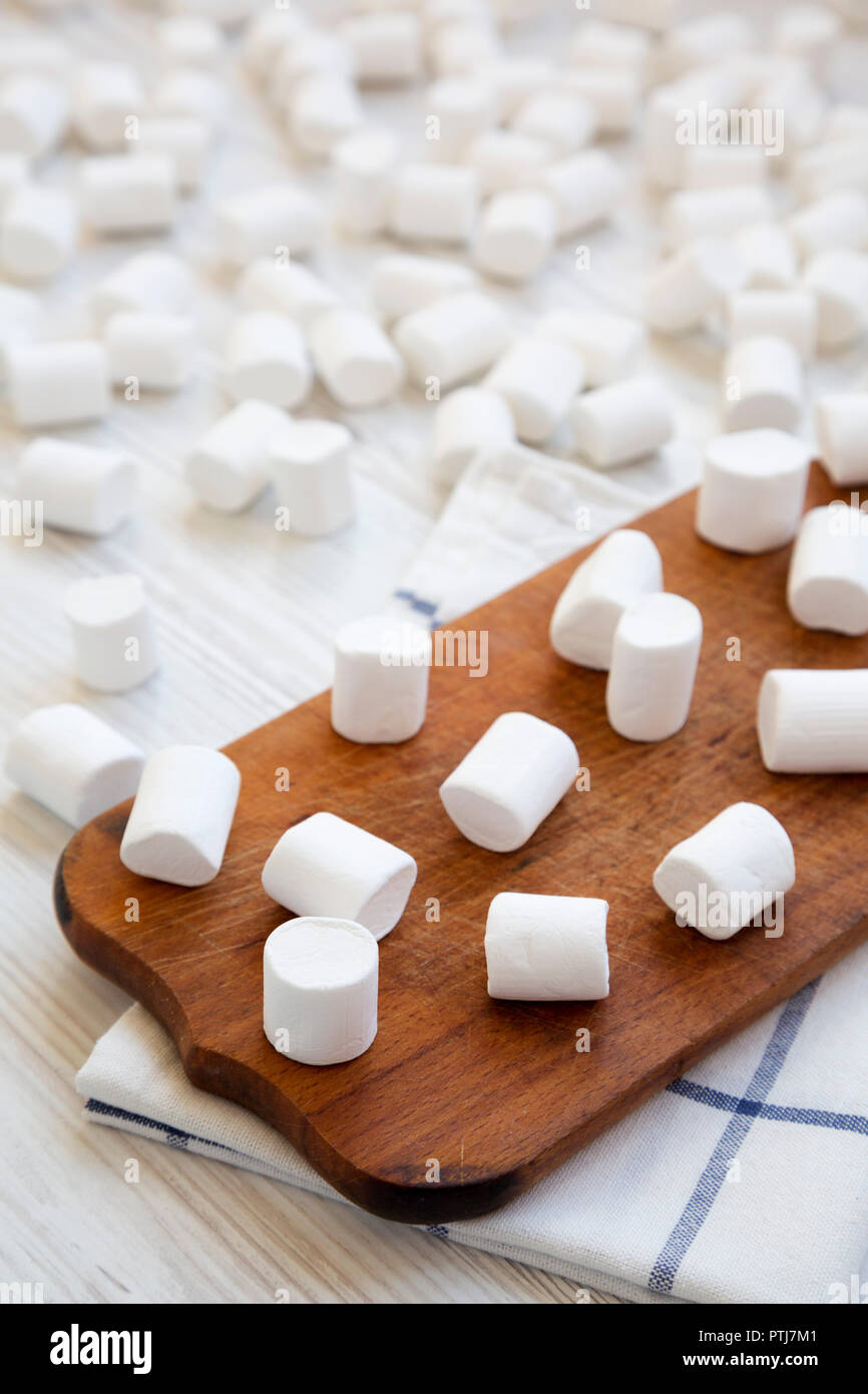 Sweet marshmallows on rustic wooden board over white wooden background ...