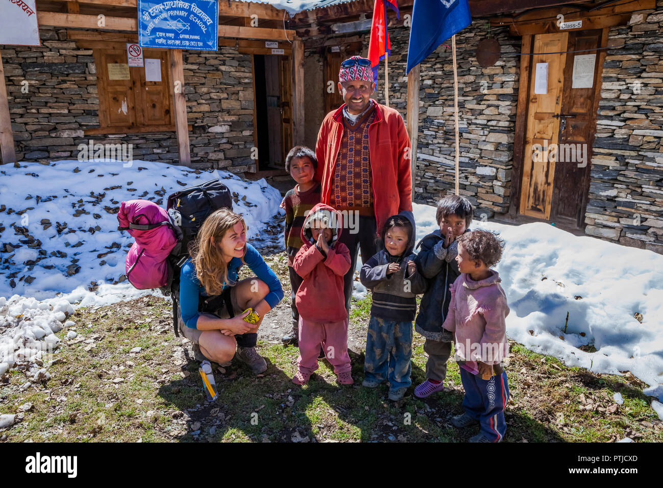 Female backpacker giving pencils to children at a school with their ...