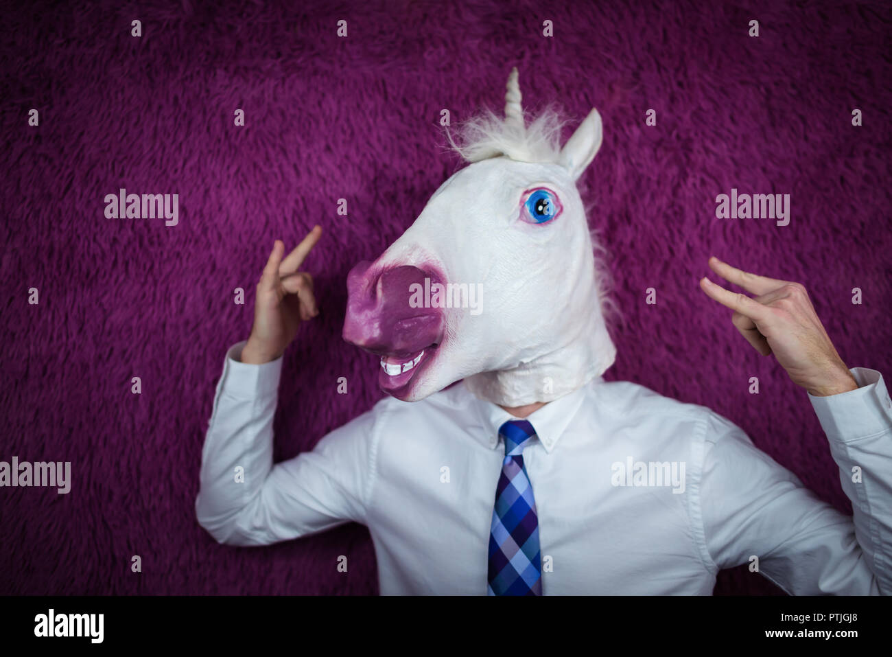 Freaky young man in comical mask stands on the purple background ...