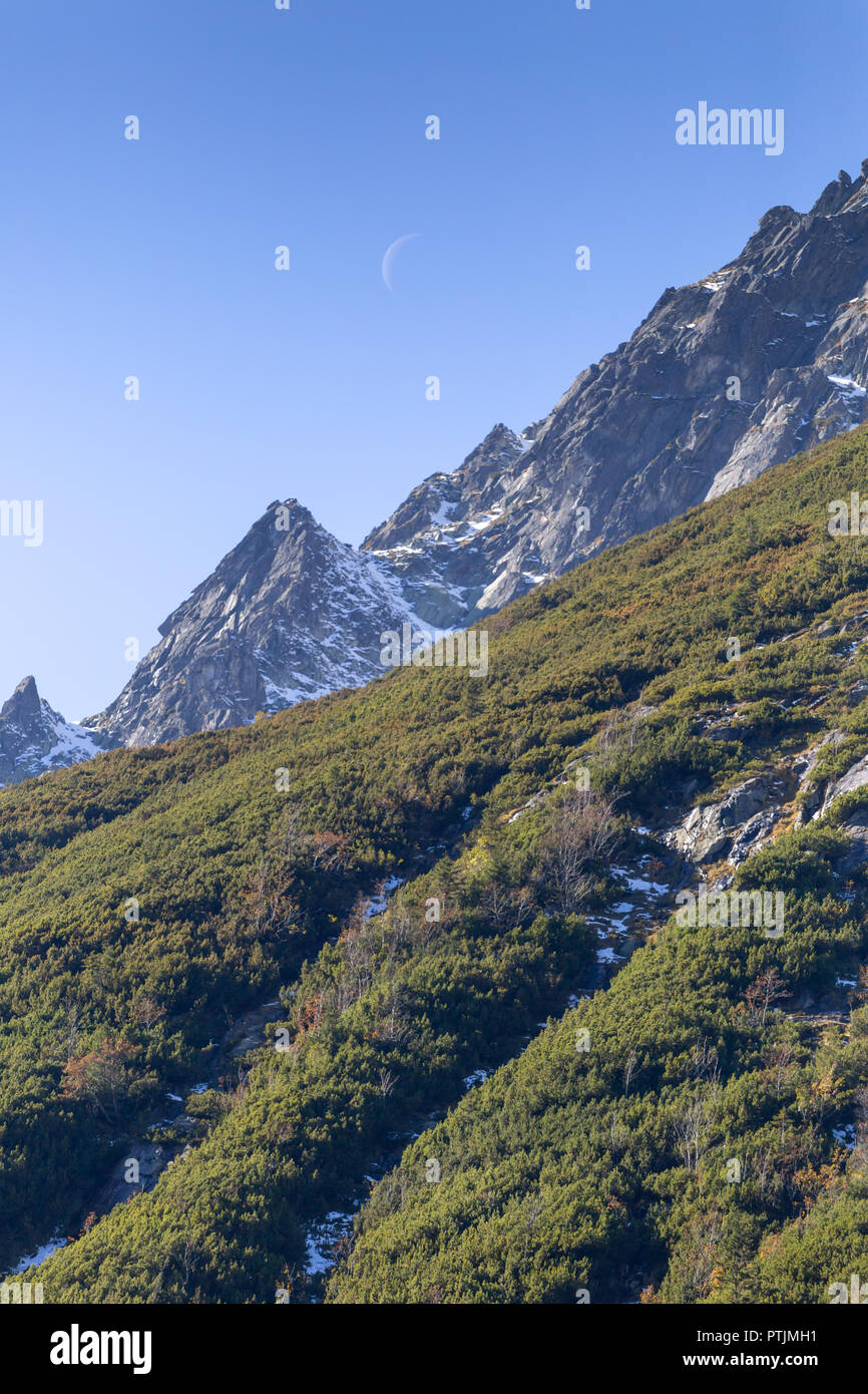 High mountains landscape. Moon over rocks and hills covered with ...