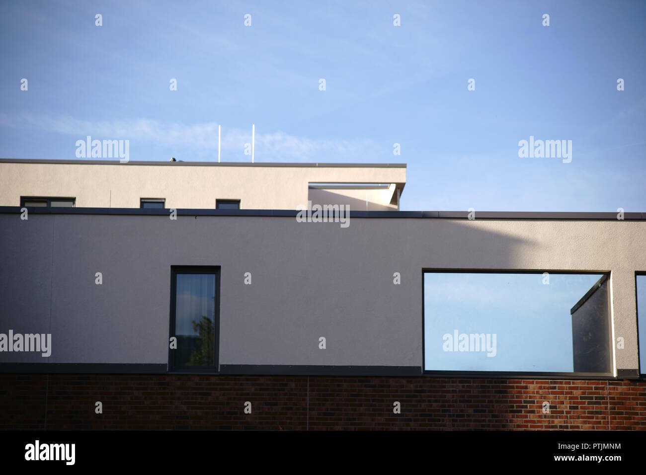 The roof edge of an apartment building in front of a blue sky with ...
