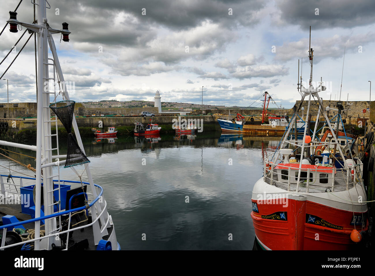Red and blue fishing boats and lighthouse at MacDuff Harbour Shipyards ...