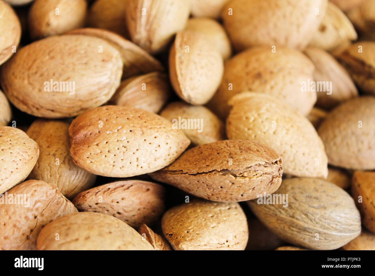 Crude almonds with nutshell for background of texture Stock Photo - Alamy