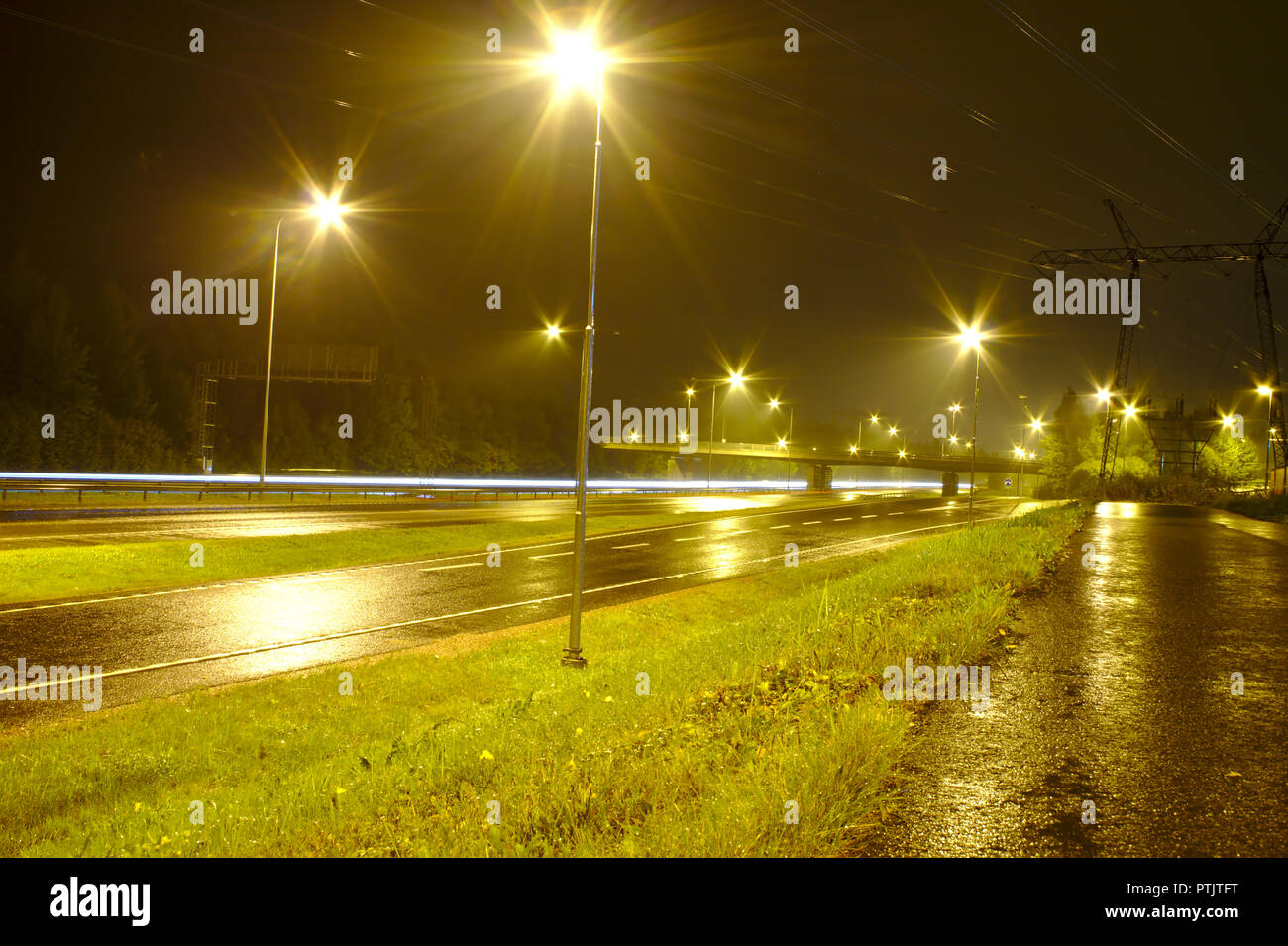 Empty motorway at rainy night with few cars passing leaving light ...