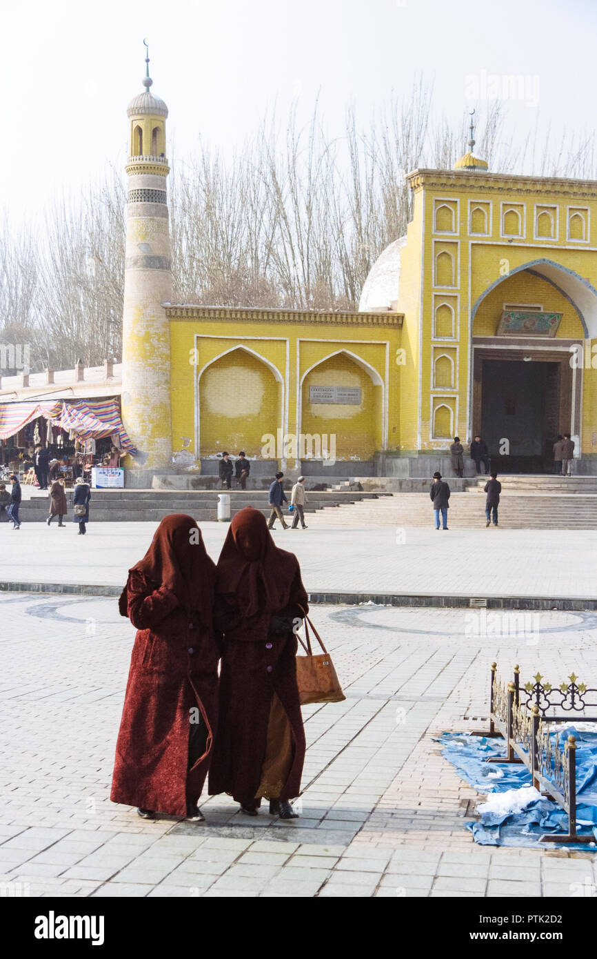Kashgar, Xinjiang, China : Two Uyghur veiled womenwalk past the yellow ...