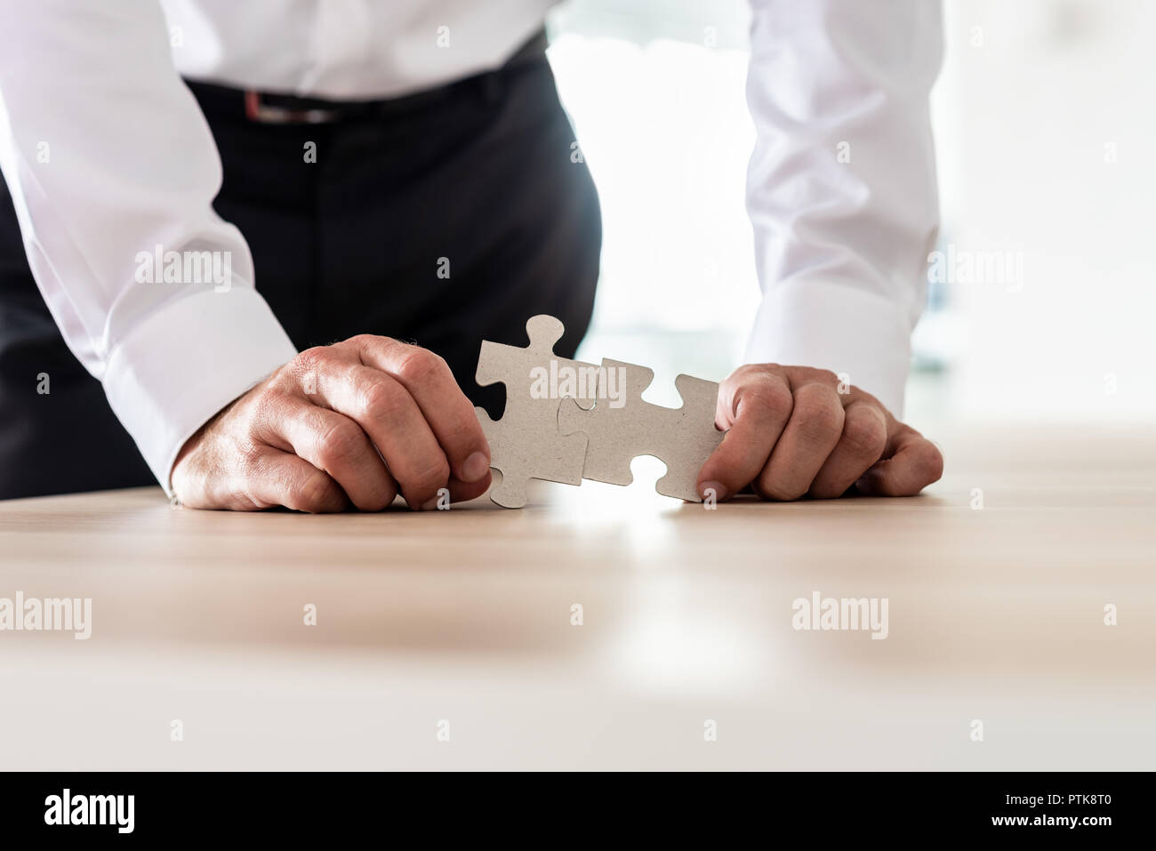 Closeup of businessman connecting two matching puzzle pieces leaning on ...