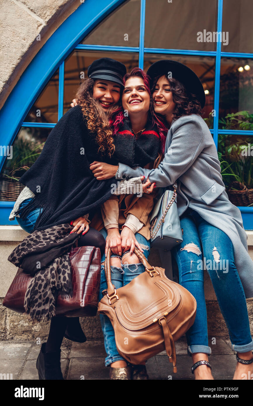 Young women hugging and laughing on city street. Best friends having ...