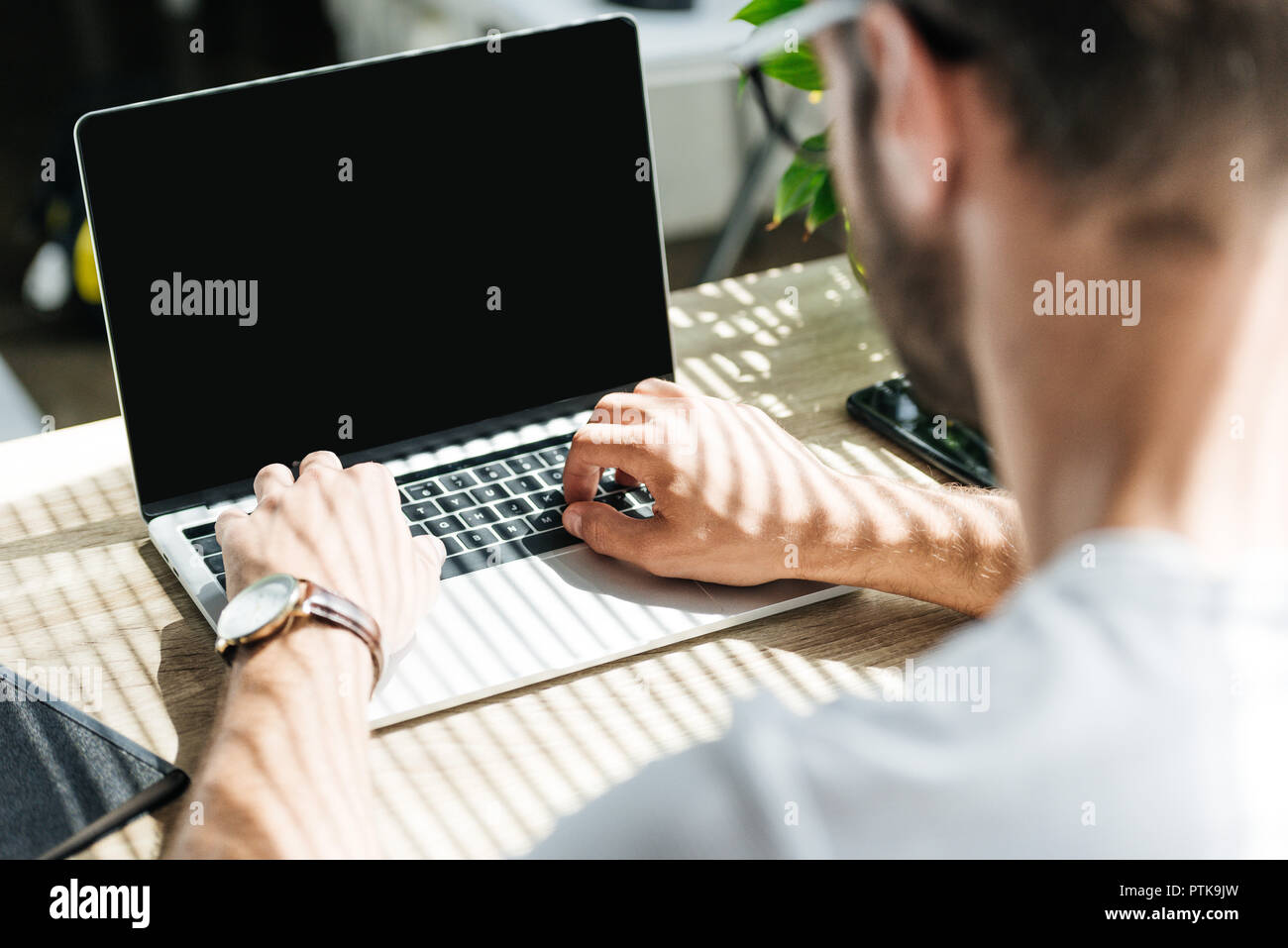 back view of man using laptop with blank screen on workplace Stock ...