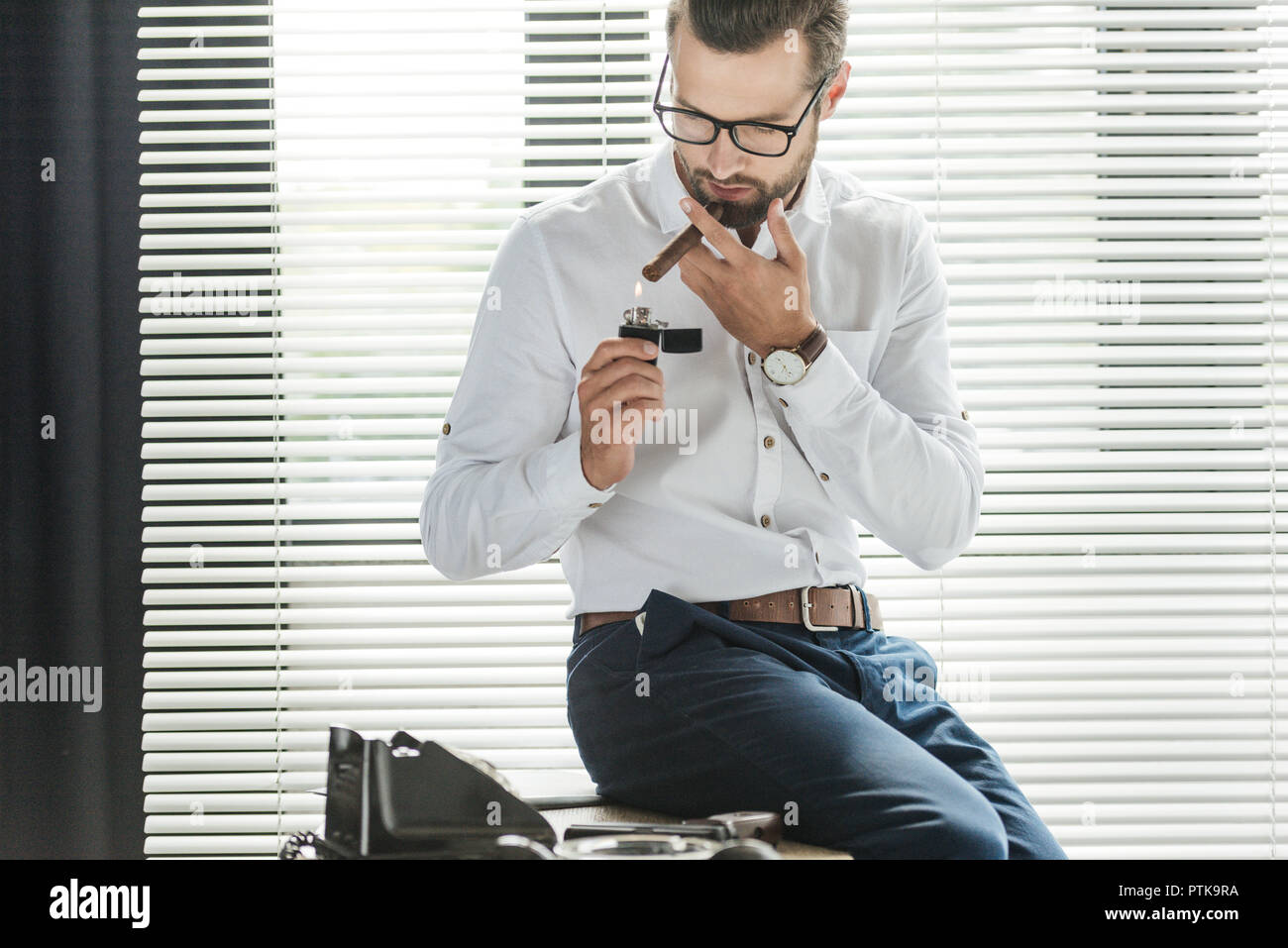businessman with lighter smoking cigar at workplace with rotary ...