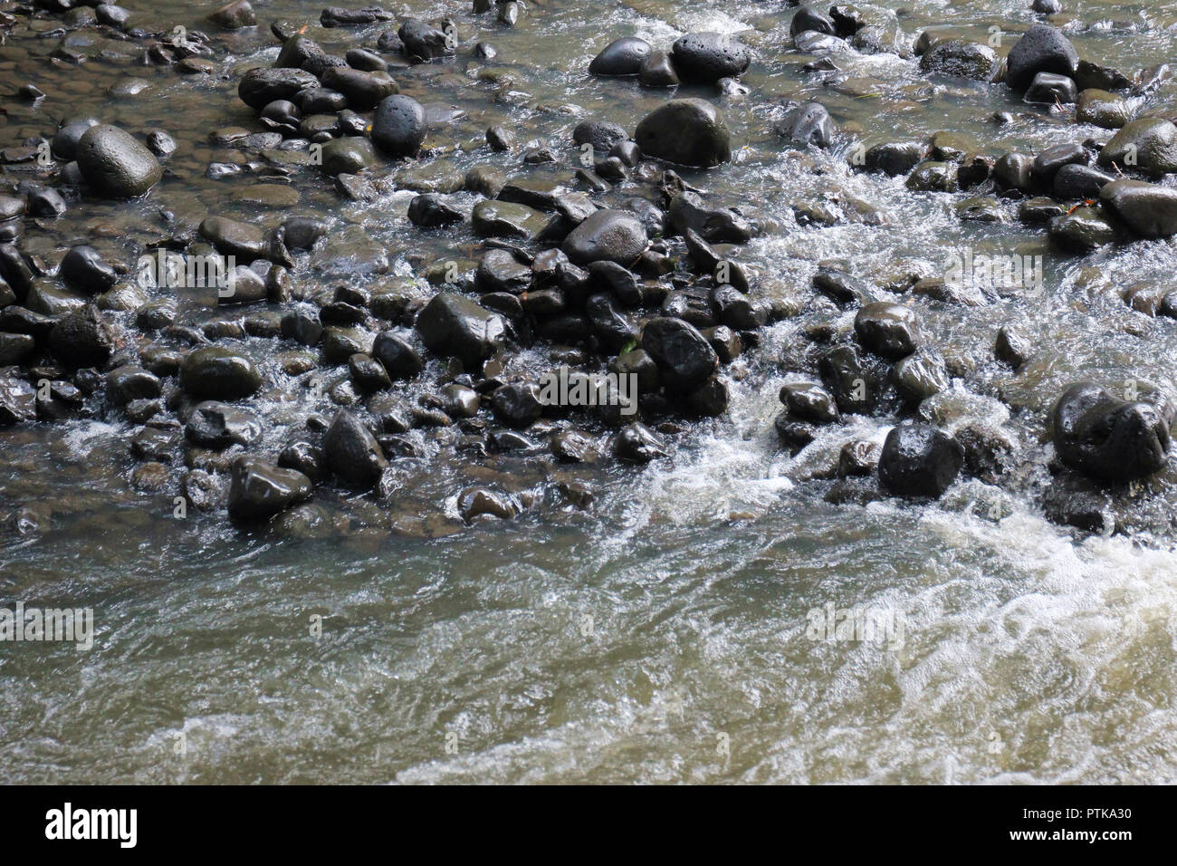 Close up of gently rushing water over slippery, wet pebbles at Ho'olawa ...