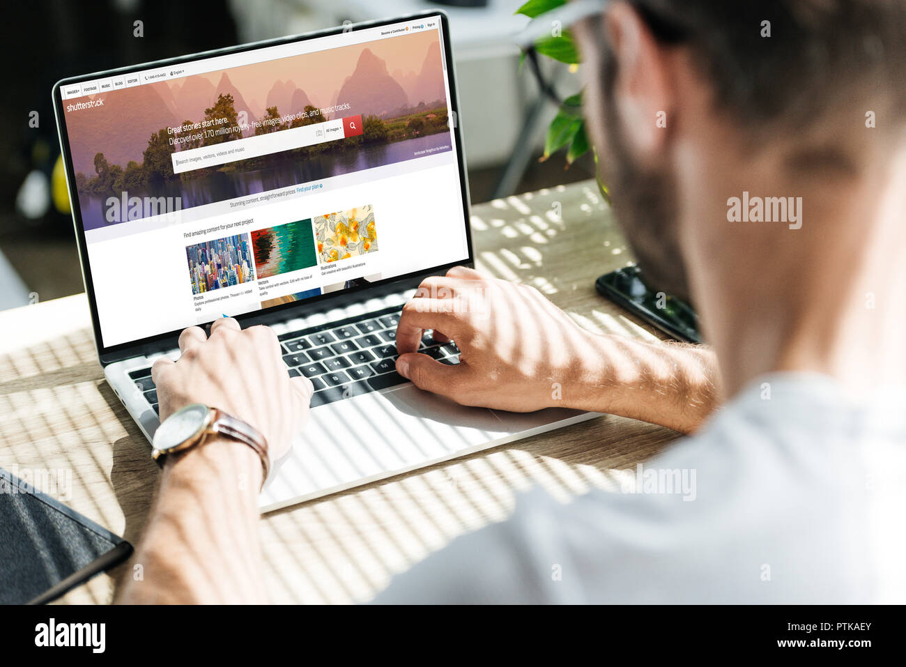 back view of man using laptop with shutterstock website on screen Stock ...