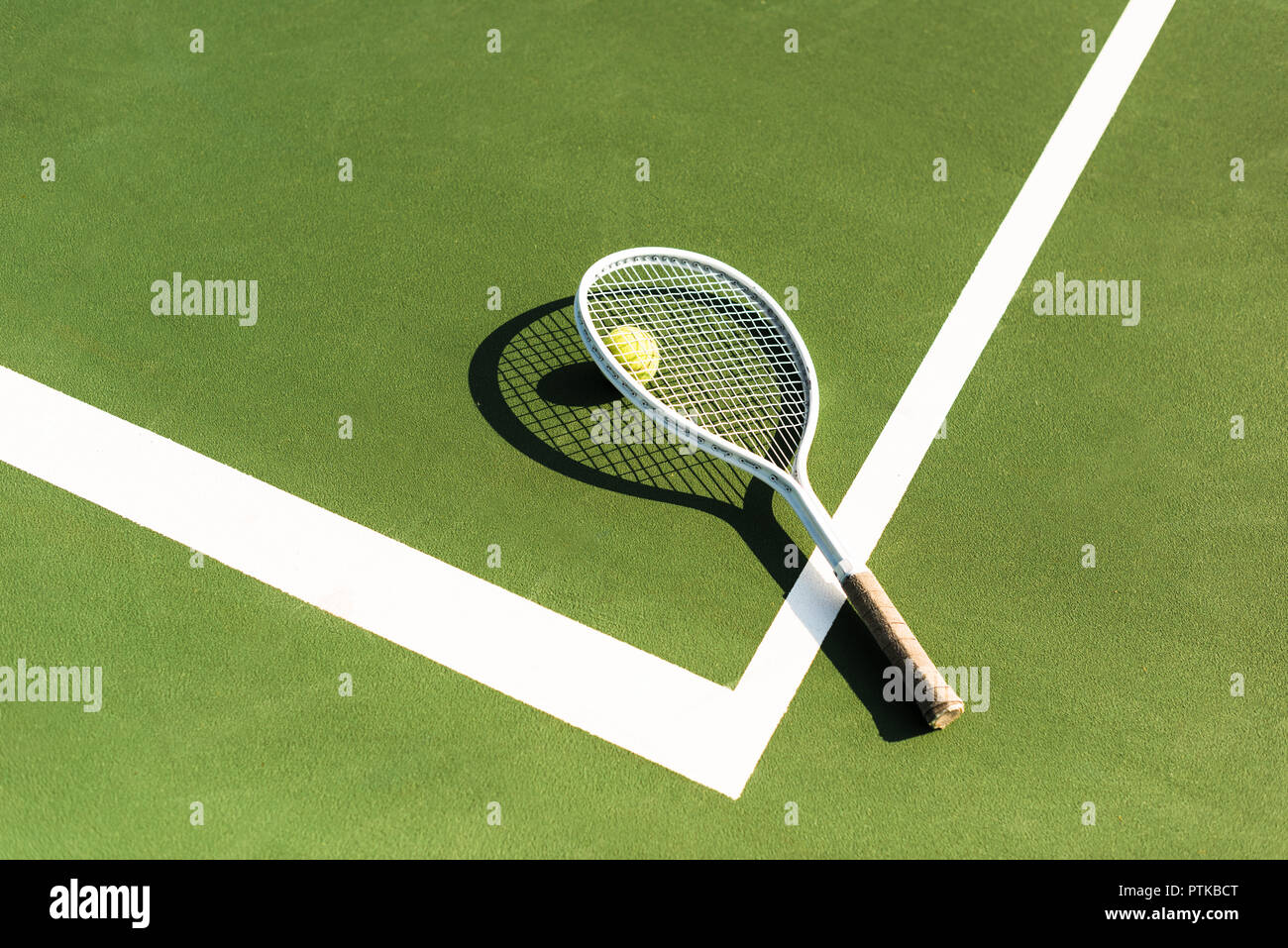 close up view of tennis racket and ball lying on green tennis court ...
