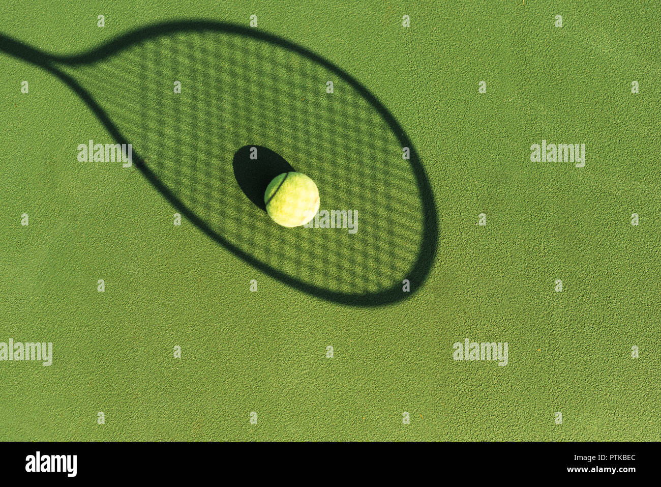 top view of tennis ball and tennis racket shadow on green tennis court ...
