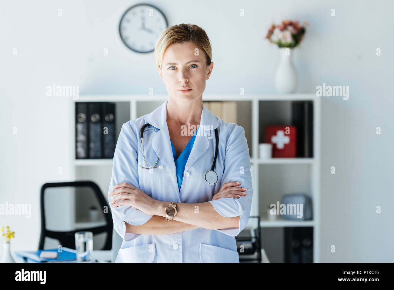 serious female doctor in white coat with stethoscope over neck standing ...