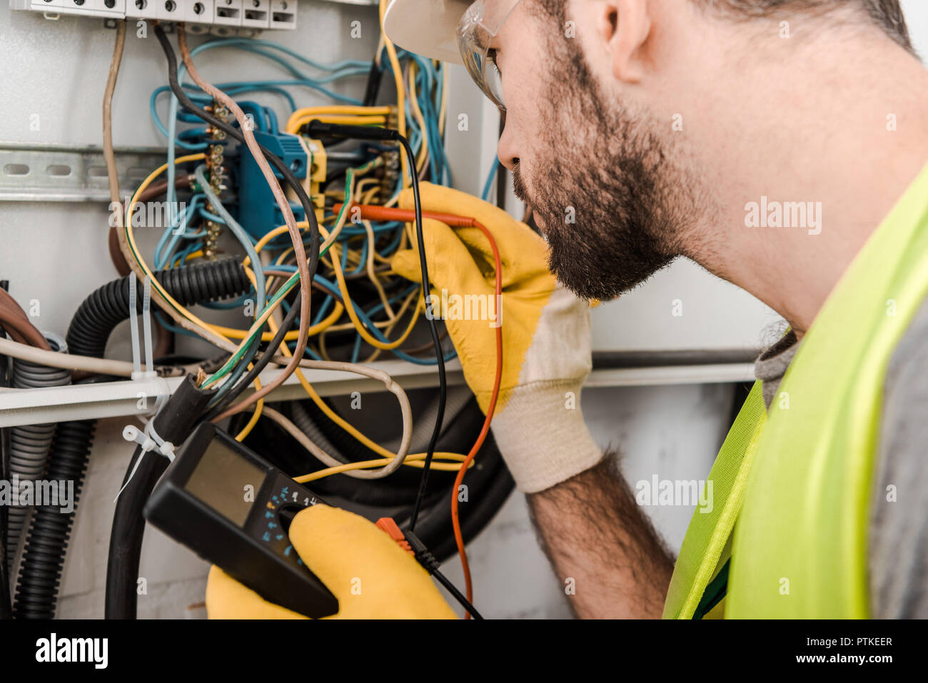 side view of electrician checking electrical box with multimetr in ...