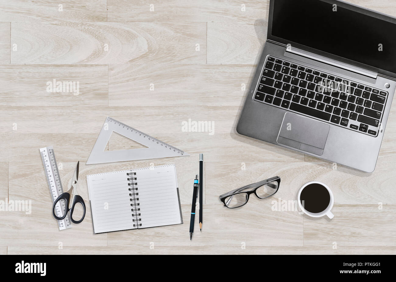 Office table with open notebook, scissor, rulers, pencils, eyeglasses ...