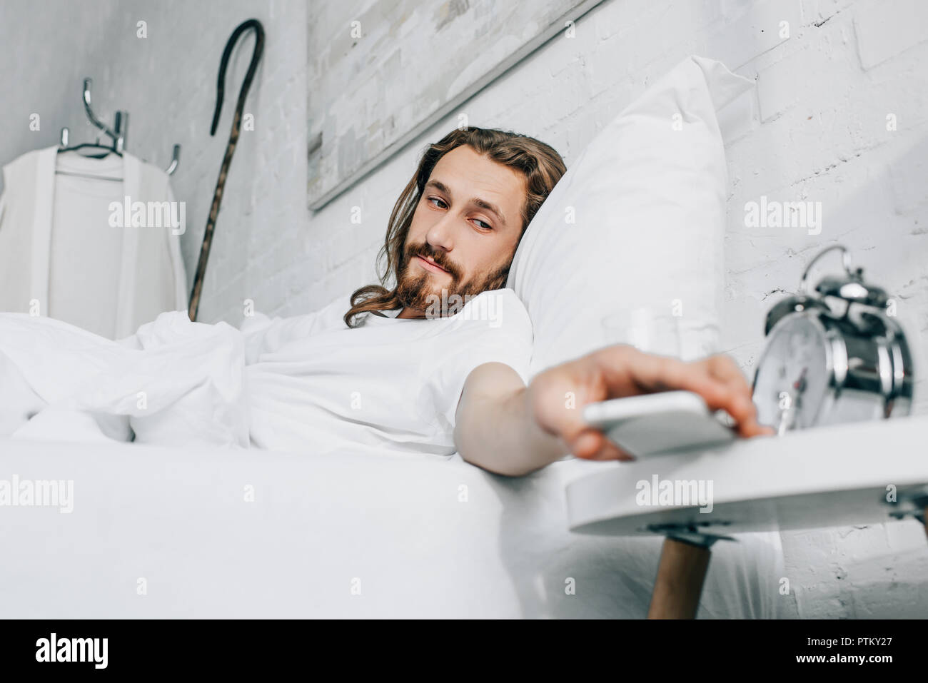 selective focus of Jesus taking smartphone in bedroom at home Stock ...