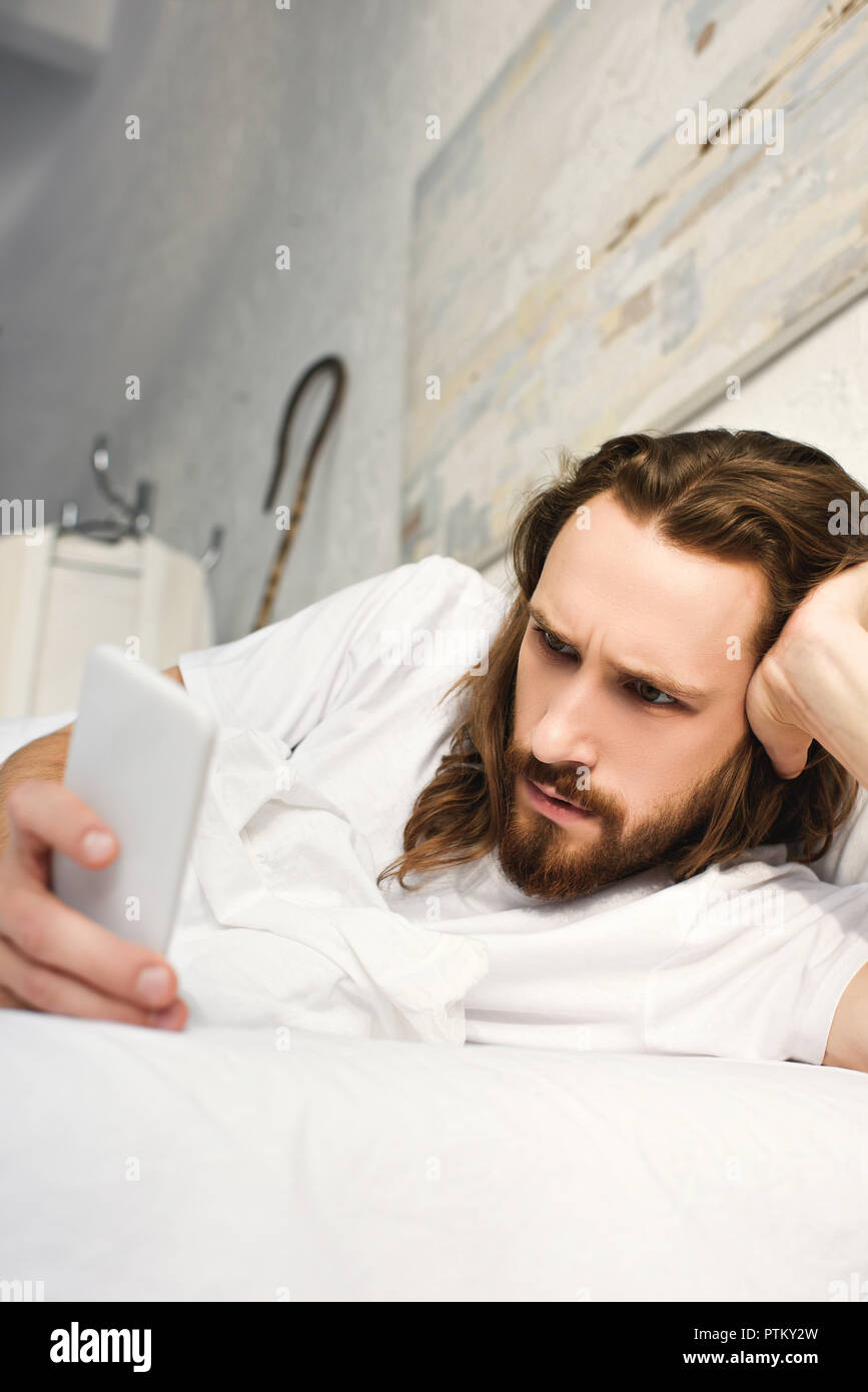 focused Jesus using smartphone in bed during morning time at home Stock ...