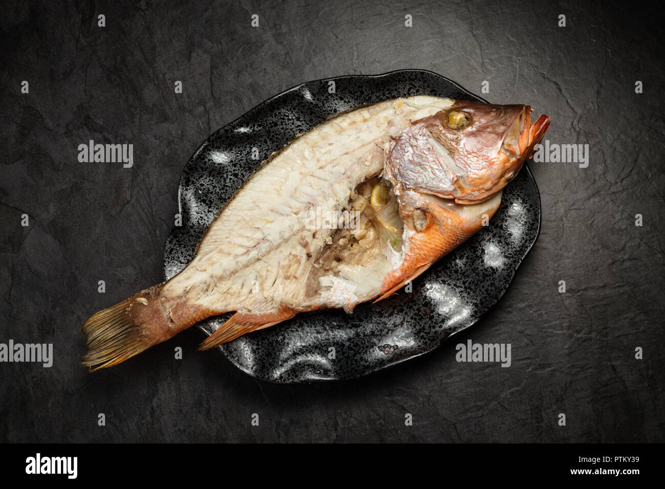 Half eating red snapper with exposed bones, on dark background Stock ...