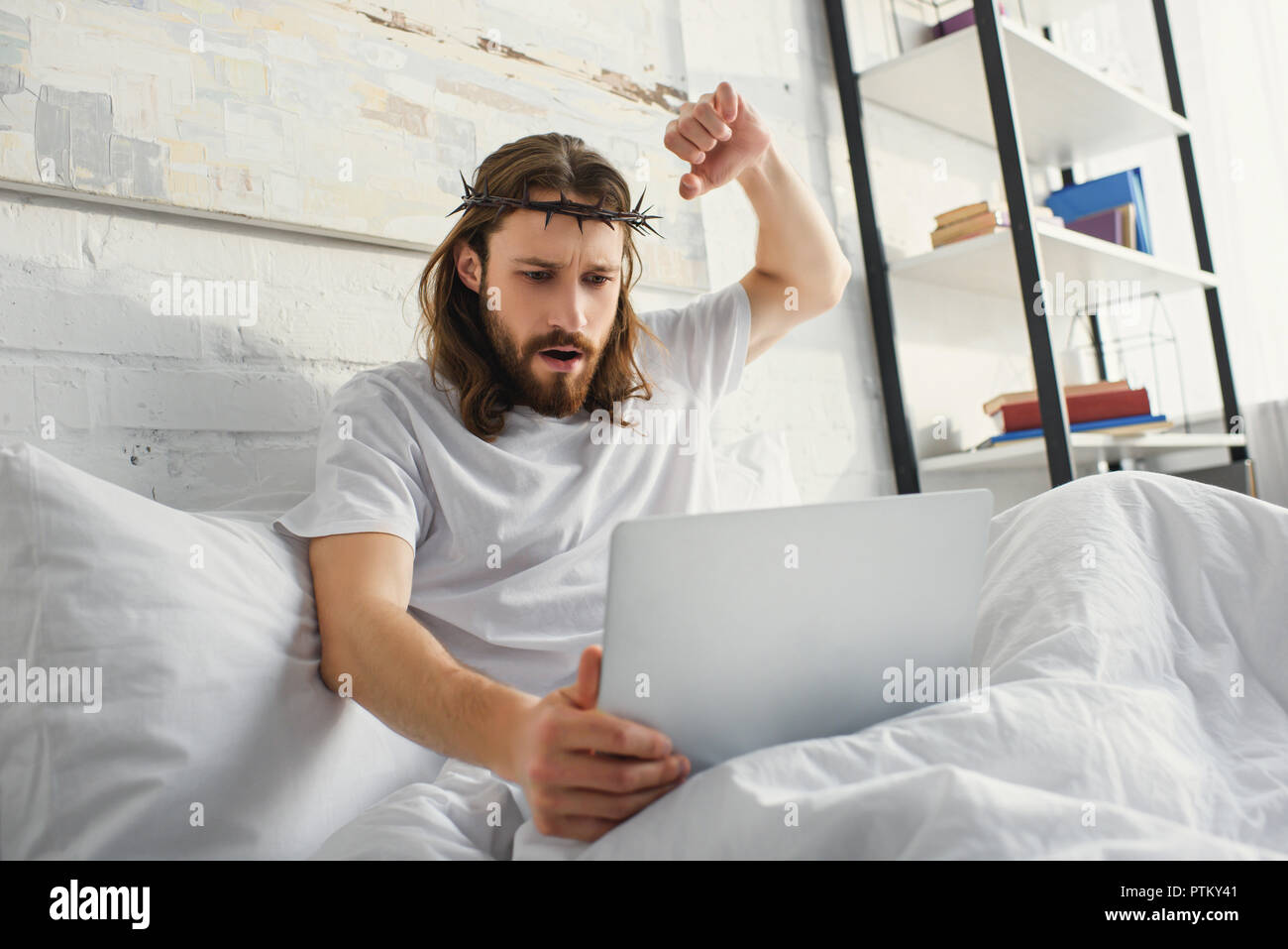 emotional Jesus using laptop and gesturing by hand in bed during ...