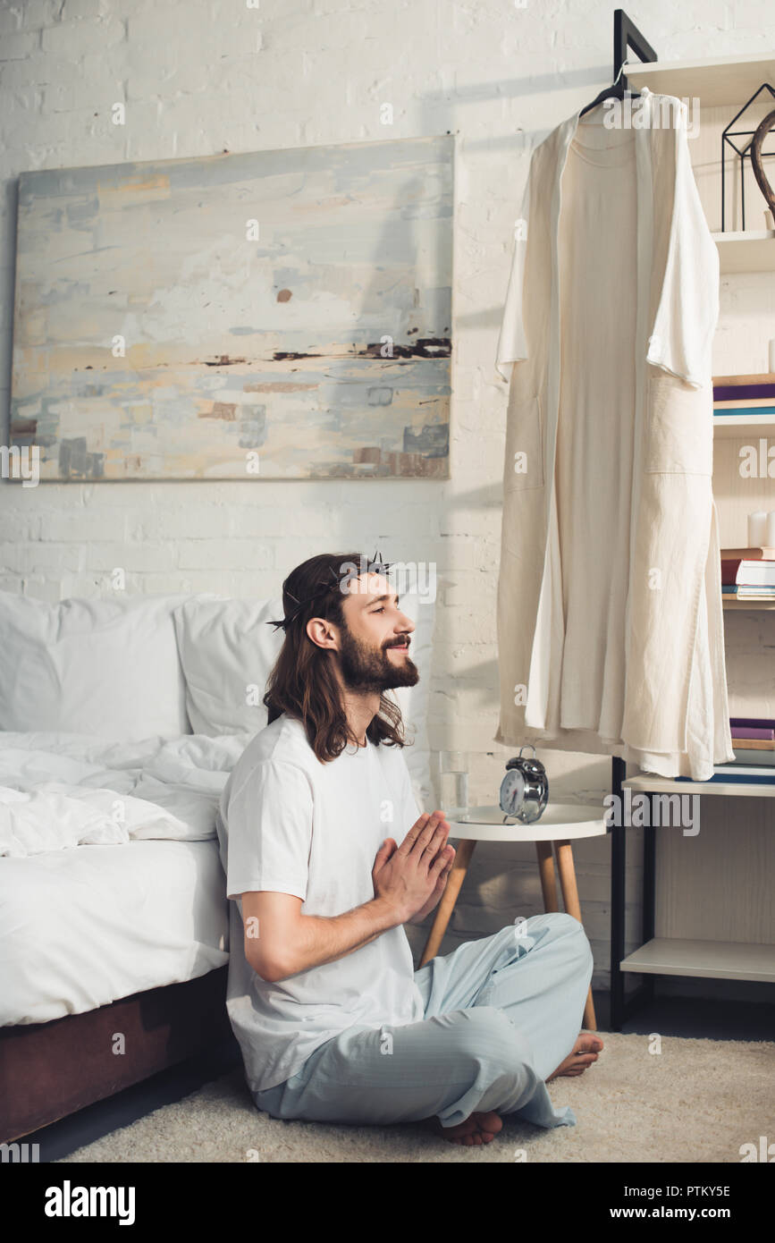 happy Jesus in crown of thorns sitting on floor in lotus position ...