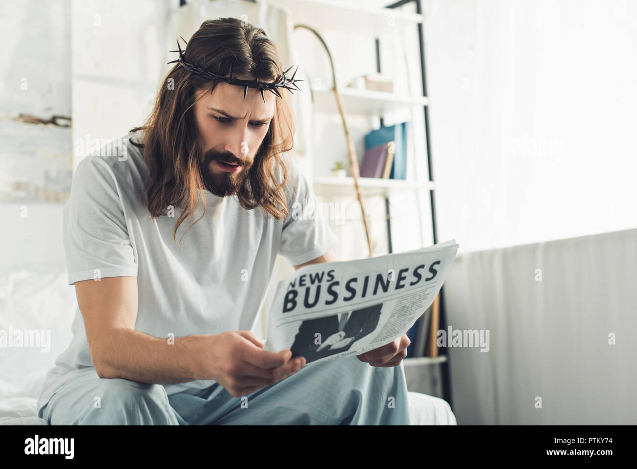 serious Jesus in crown of thorns reading business newspaper in bedroom ...