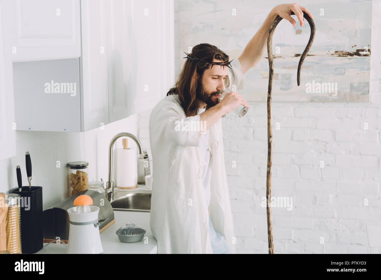 tired Jesus in crown of thorns drinking water and standing with wooden ...