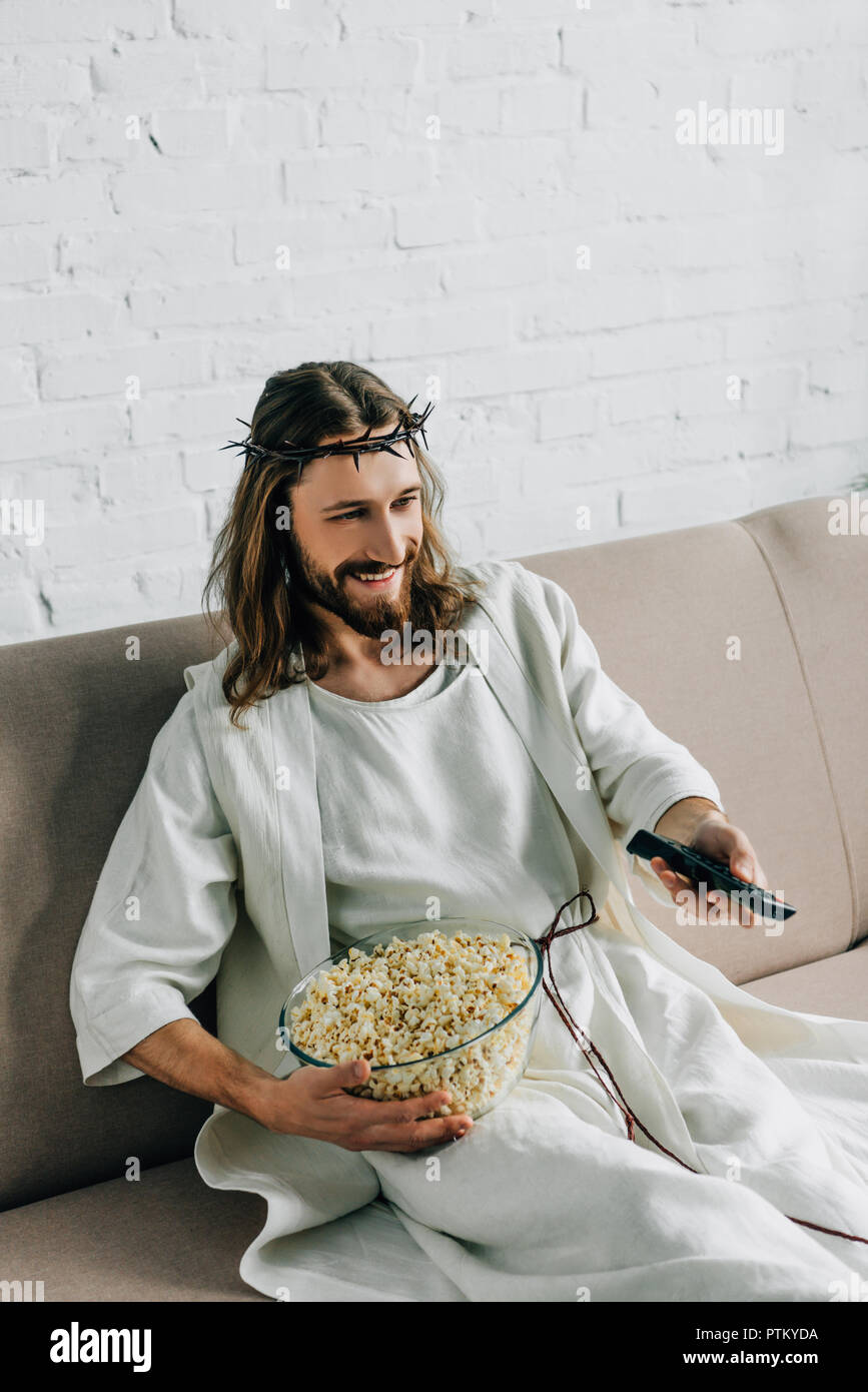 high angle view of happy Jesus in crown of thorns watching tv and ...