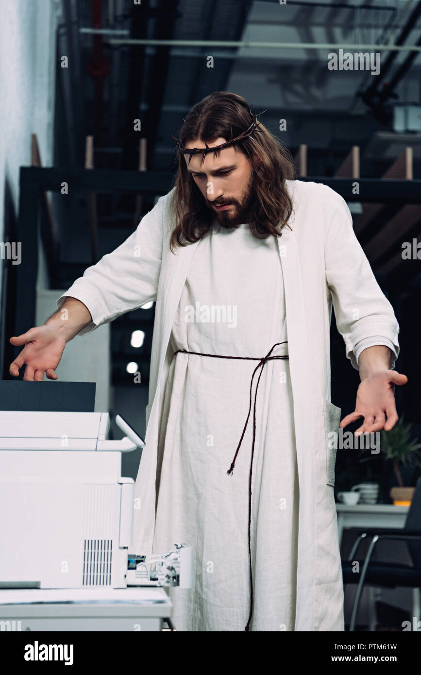 emotional Jesus in crown of thorns and robe gesturing by hands and ...