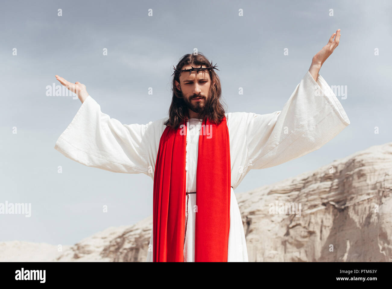 low angle view of Jesus in robe, red sash and crown of thorns standing ...