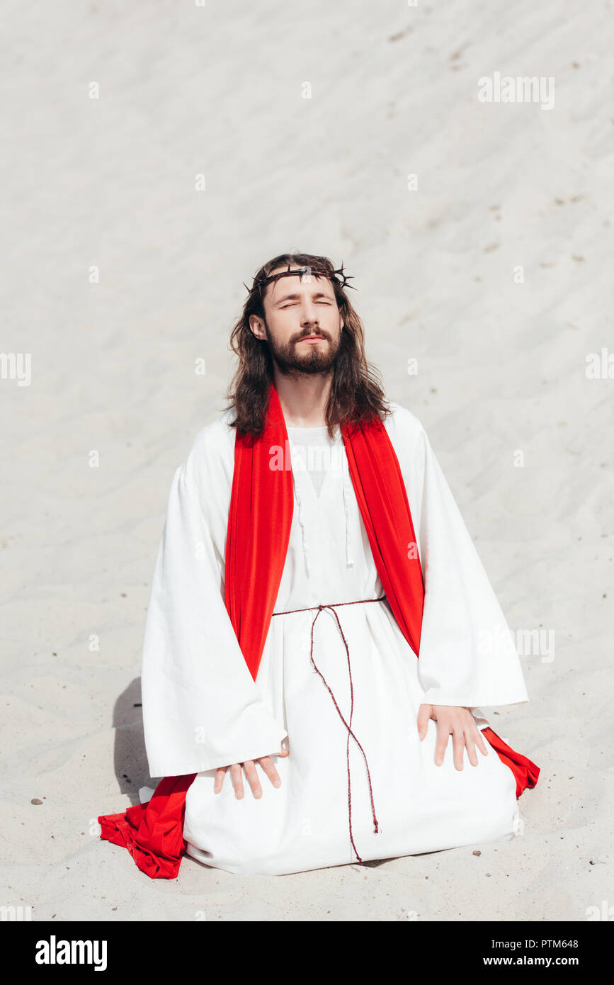 Jesus in robe, red sash and crown of thorns standing on knees with ...