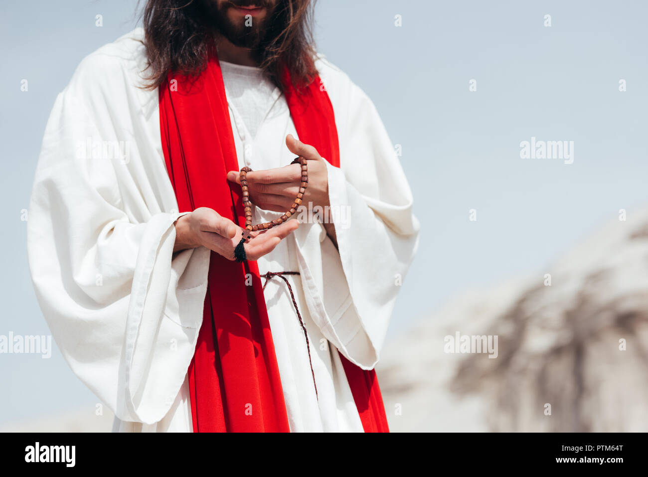 cropped image Jesus with long hair in robe and red sash holding wooden ...