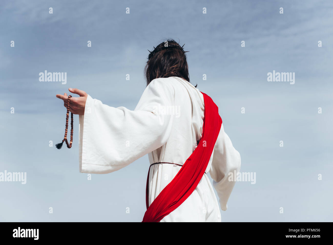 back view of Jesus in robe, red sash and crown of thorns holding rosary ...