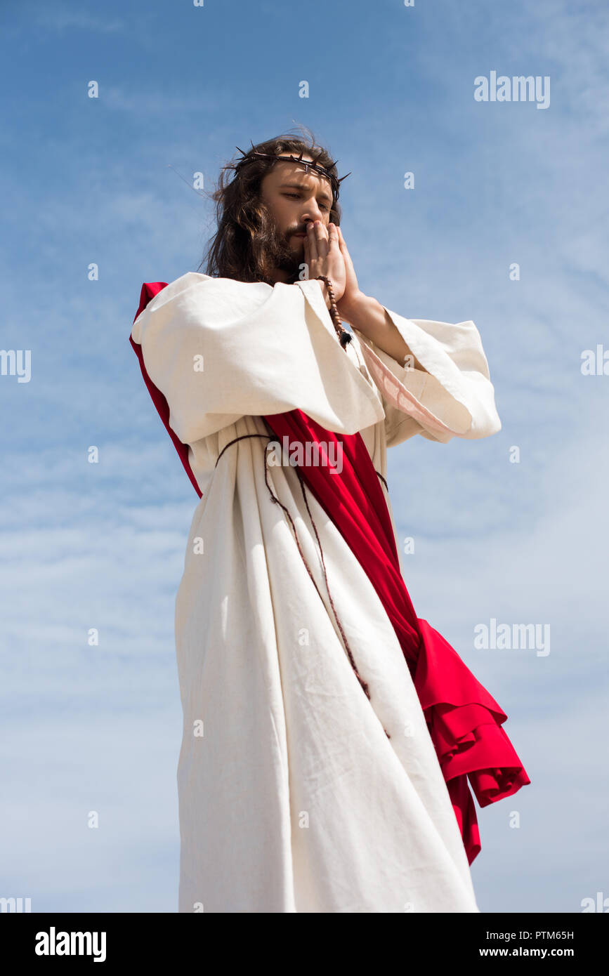 low angle view of Jesus in robe, red sash and crown of thorns holding ...