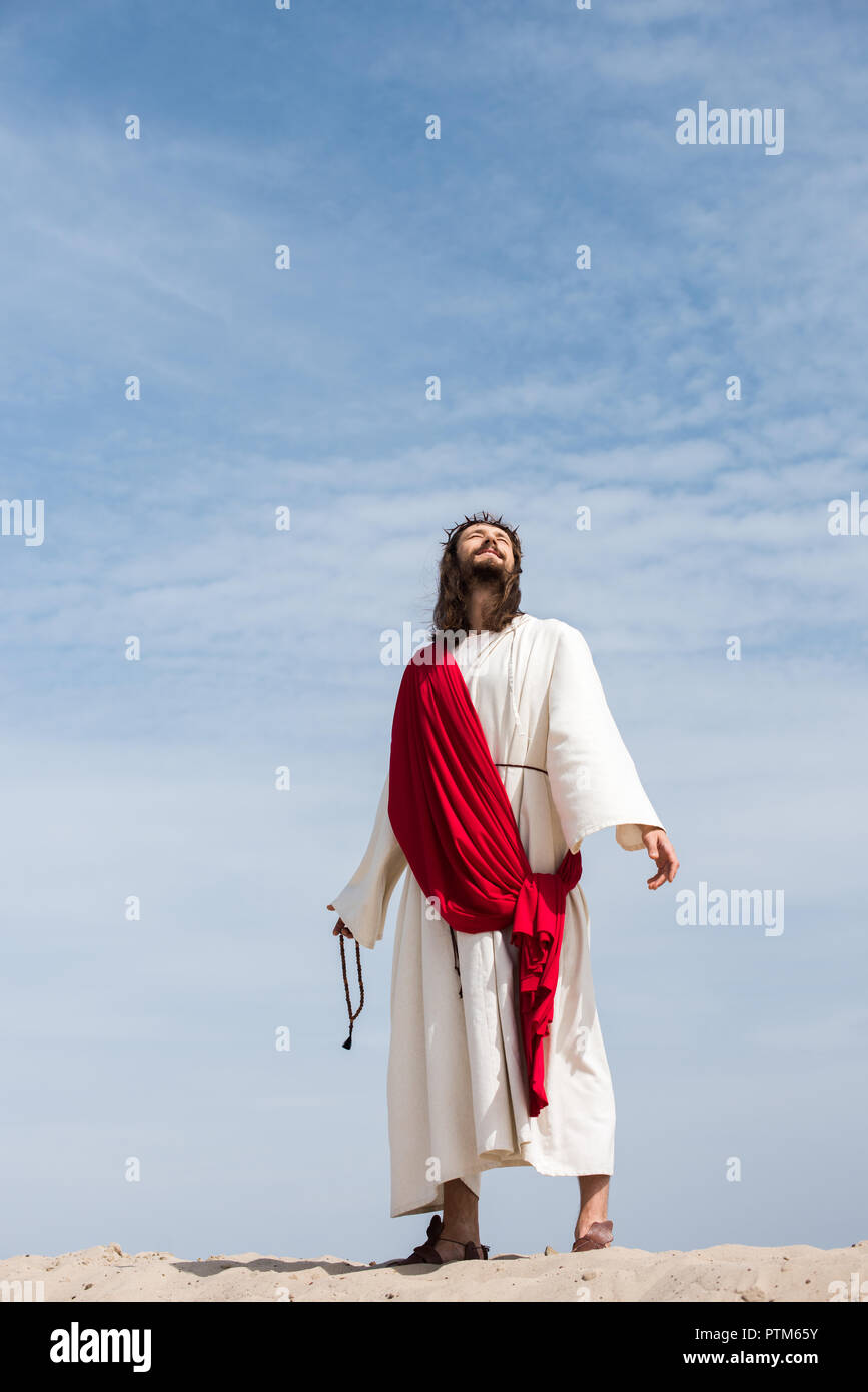 Jesus in robe, red sash and crown of thorns holding rosary and looking ...