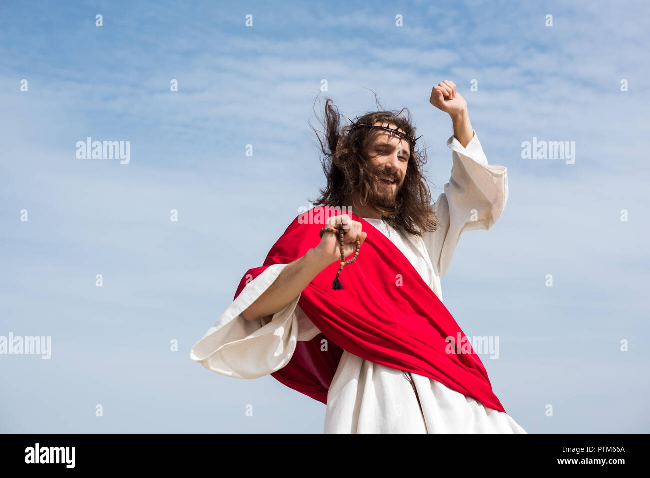 low angle view of Jesus in robe, red sash and crown of thorns having ...
