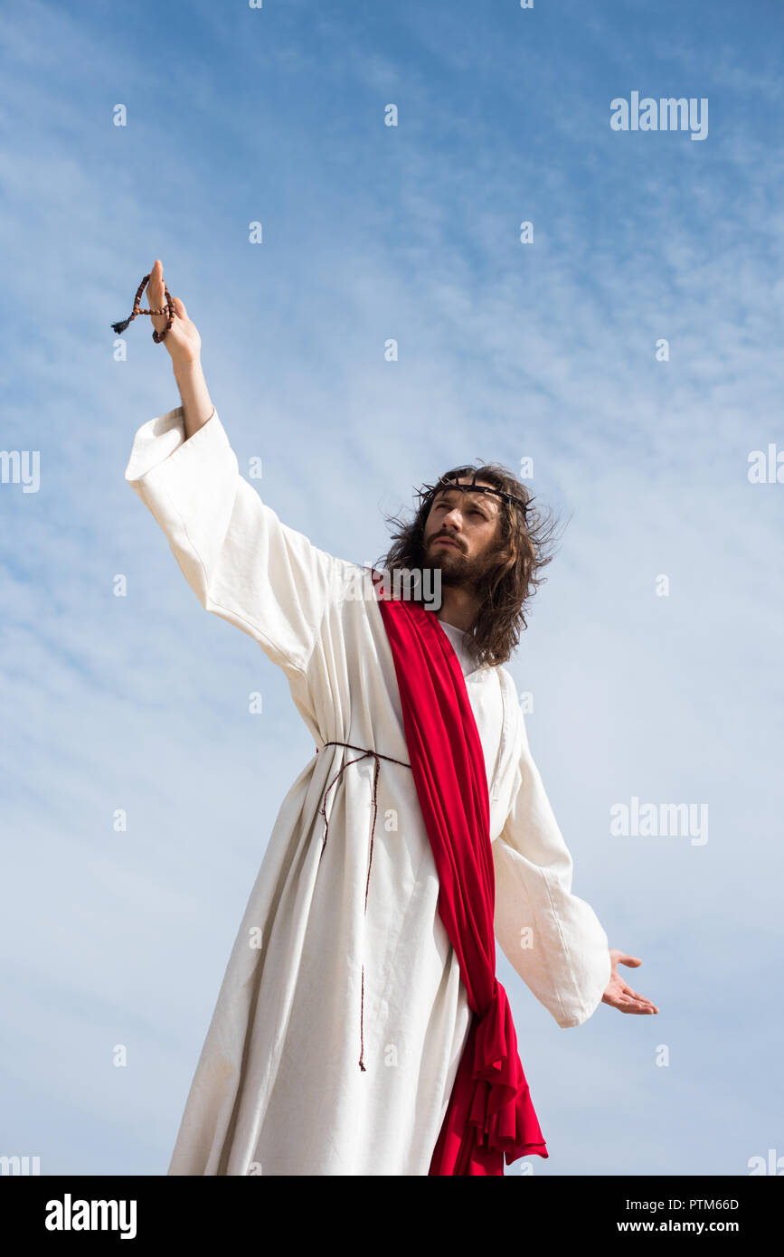 low angle view of Jesus in robe, red sash and crown of thorns holding ...