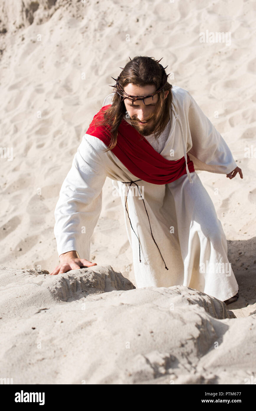high angle view of Jesus in robe, red sash and crown of thorns climbing ...