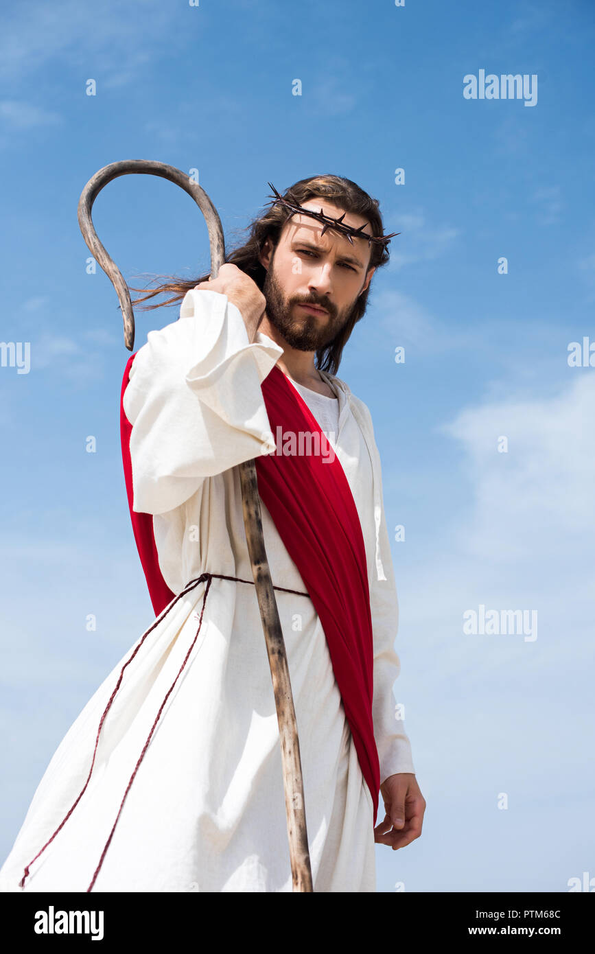 low angle view of Jesus in robe, red sash and crown of thorns standing ...