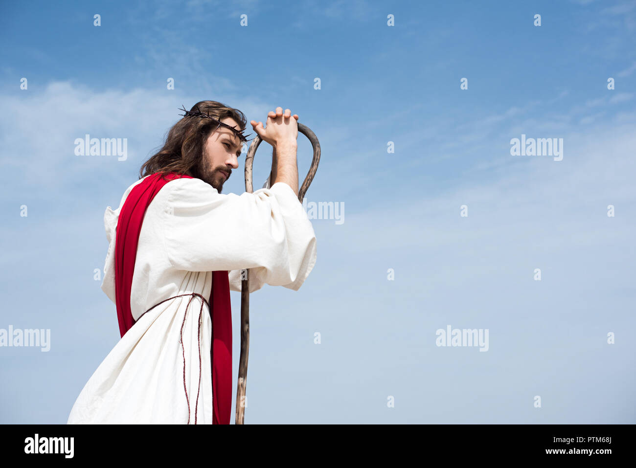 side view of Jesus in robe, red sash and crown of thorns leaning on ...