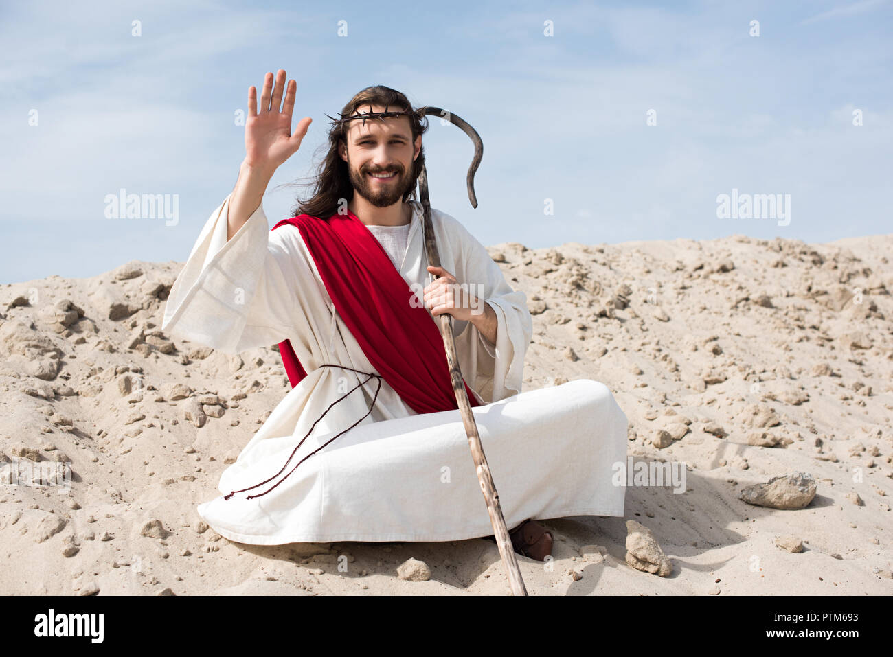 Jesus in robe, red sash and crown of thorns sitting in lotus position ...
