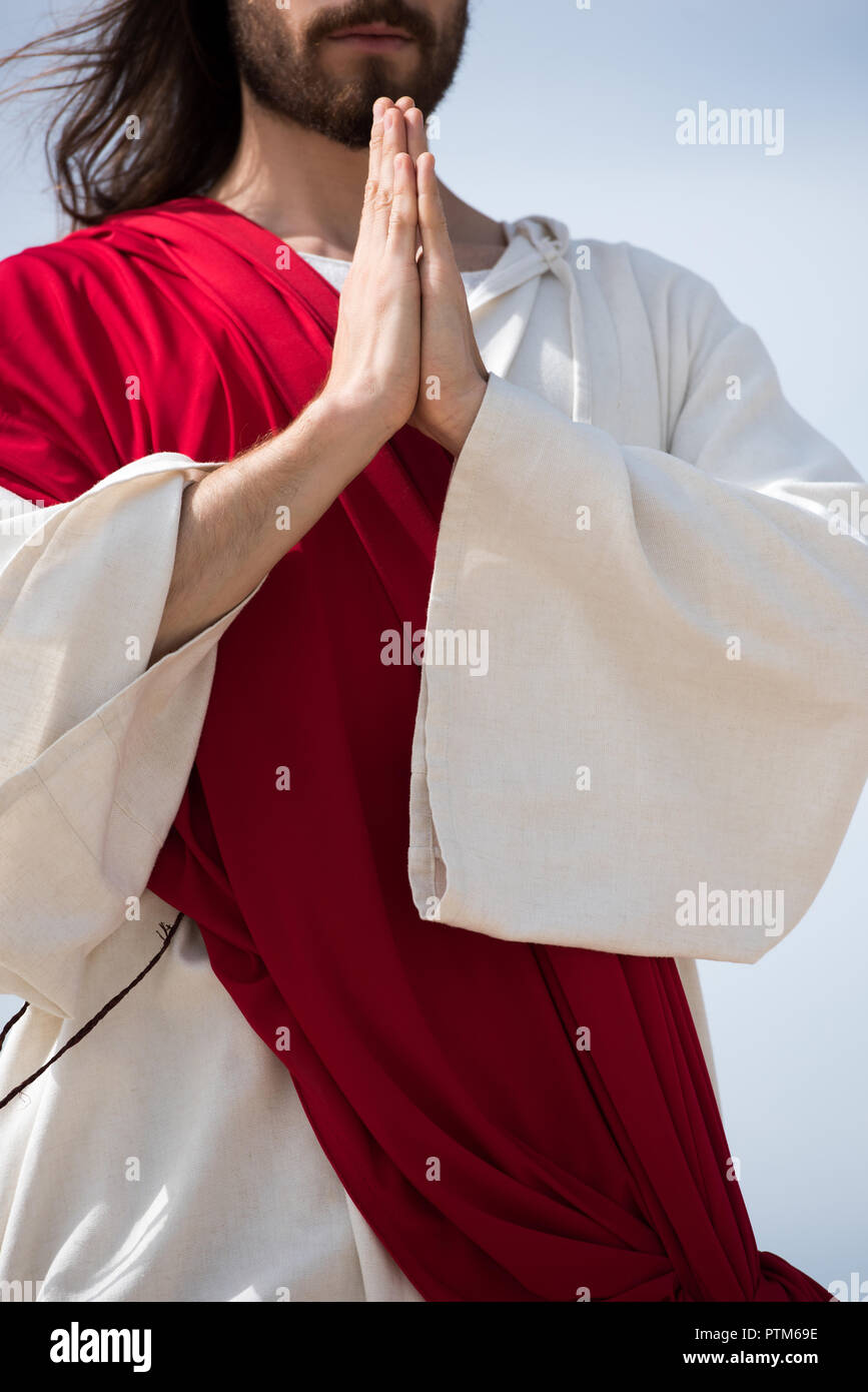 cropped image of Jesus in robe and red sash praying outdoors Stock ...