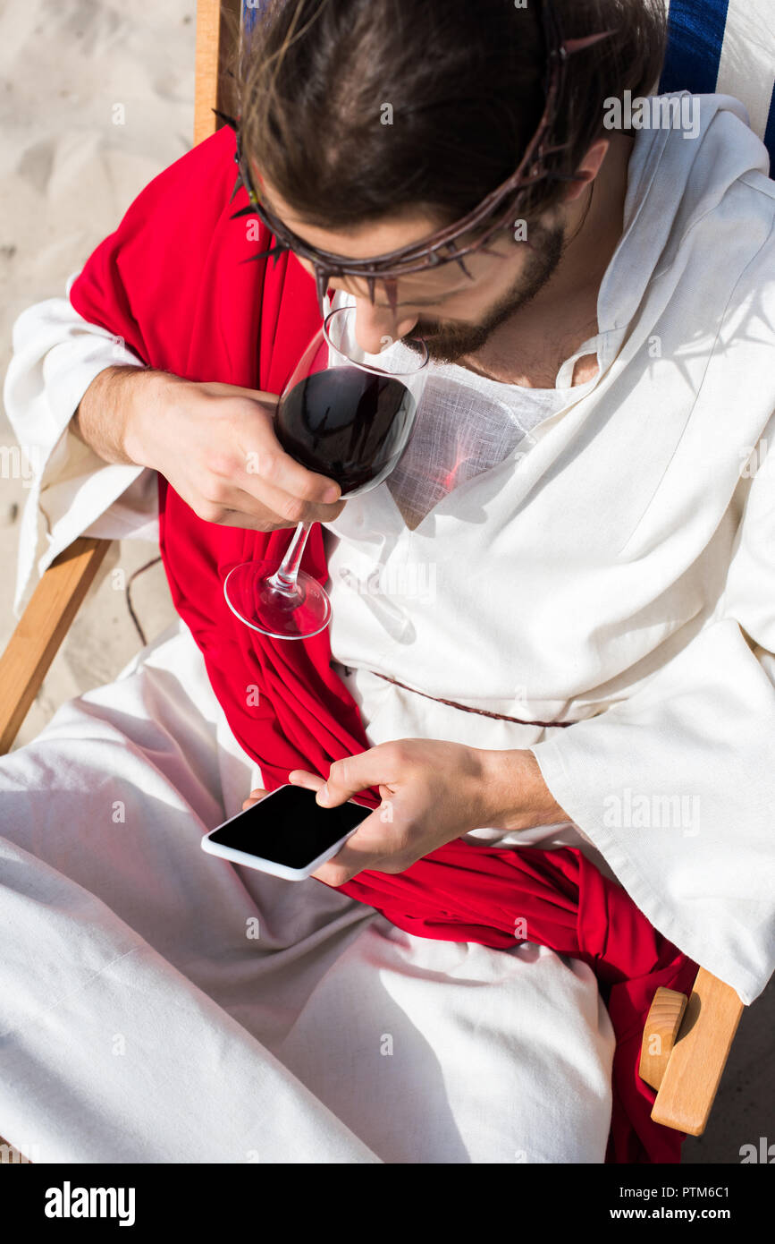 high angle view of Jesus resting on sun lounger, drinking wine and ...